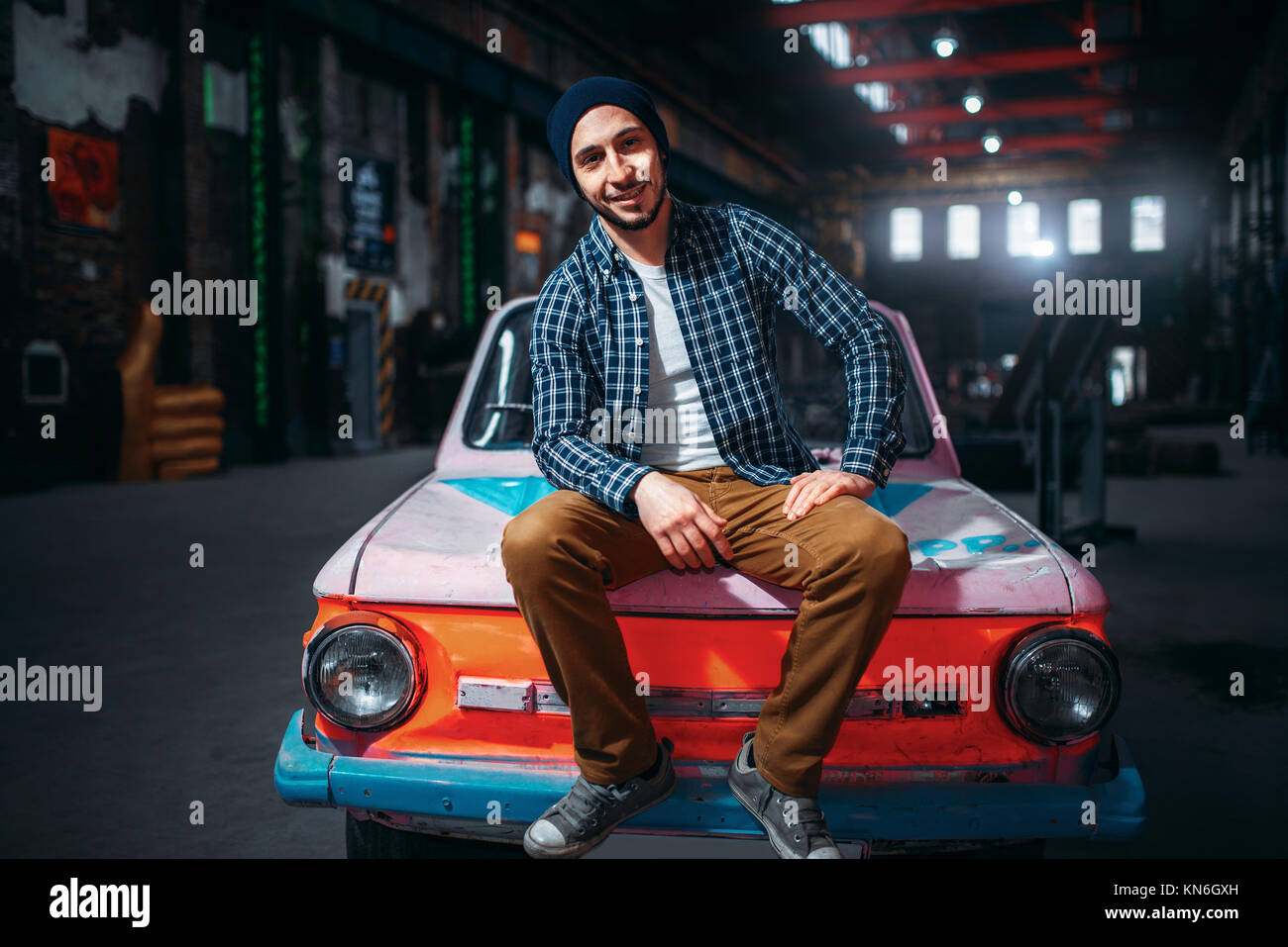 Stalker, male traveler pose against retro car, factory interior on ...