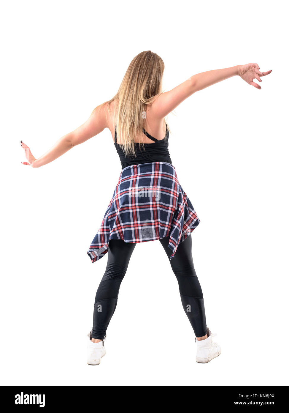 Rear view of young blonde woman dancing with outstretched spread arms ...