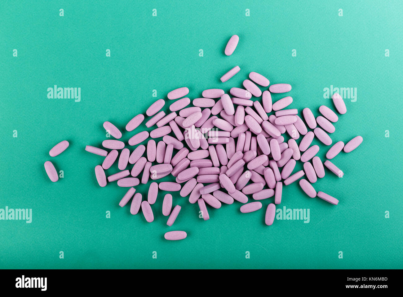 large pink tablets scattered on a green background. treatment of ...