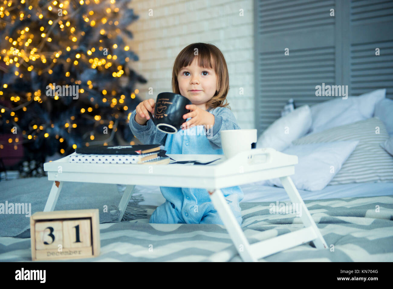 New Year's Eve, December 31. Cute little girl in pajama with cup near ... New Year's Eve, December 31. Cute little girl in pajama with cup near ...