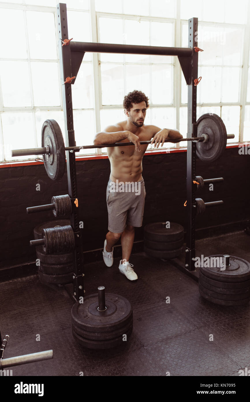 Muscular man leaning over barbell after workout in gym. Male taking ...
