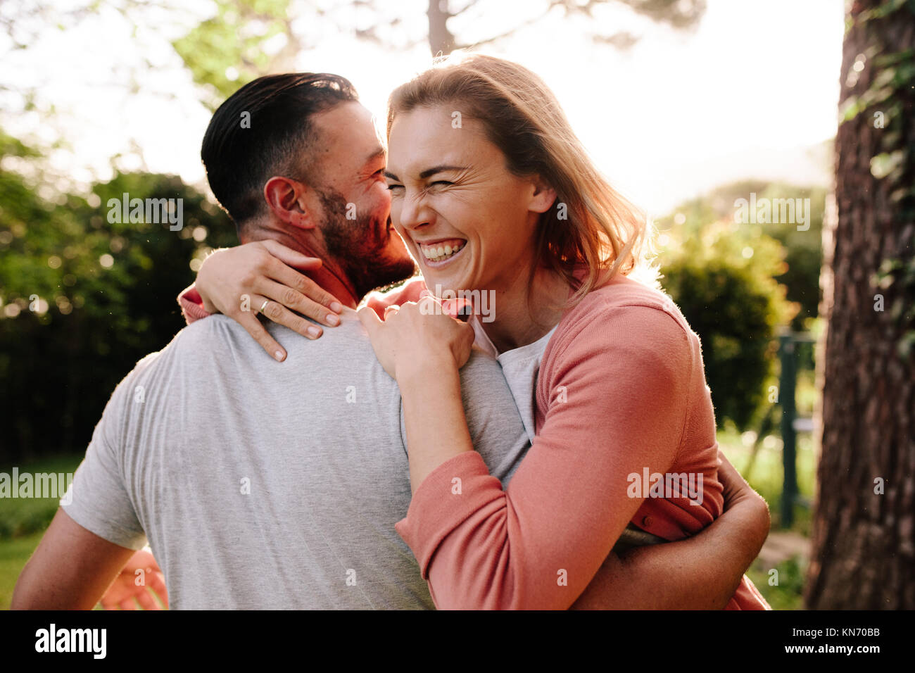 Happy young couple having fun outdoors in park. Man hugging smiling ...