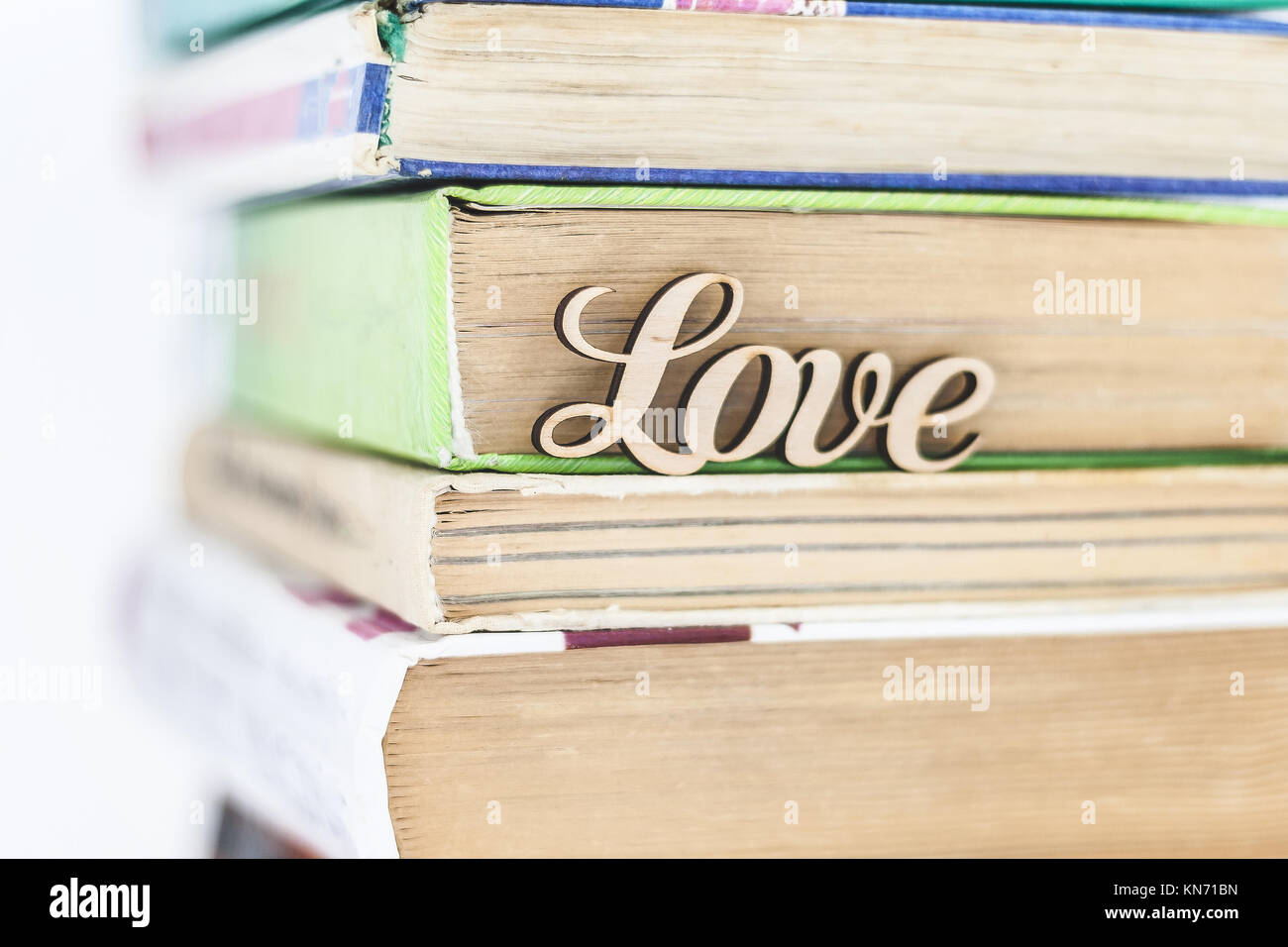 on a stack of old books wooden word love Stock Photo - Alamy