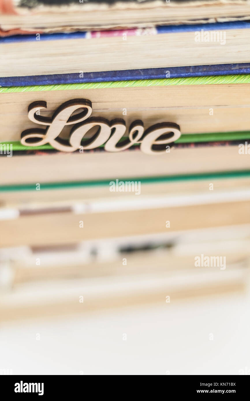 on a stack of old books wooden word love Stock Photo - Alamy