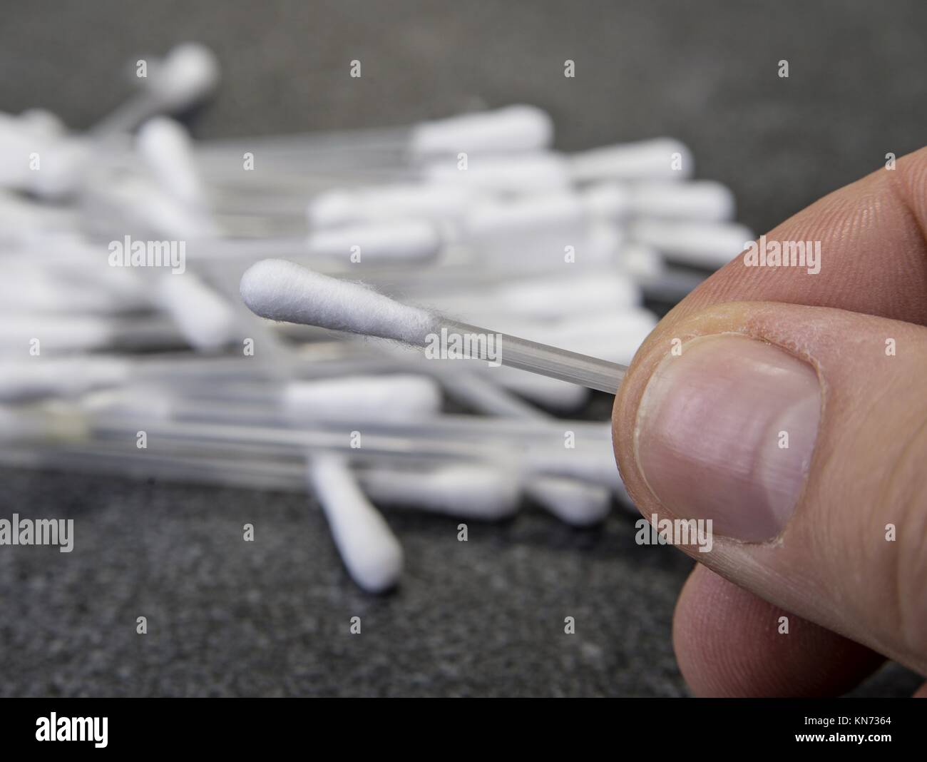 Cotton swab in the fingers to clean ear Stock Photo - Alamy
