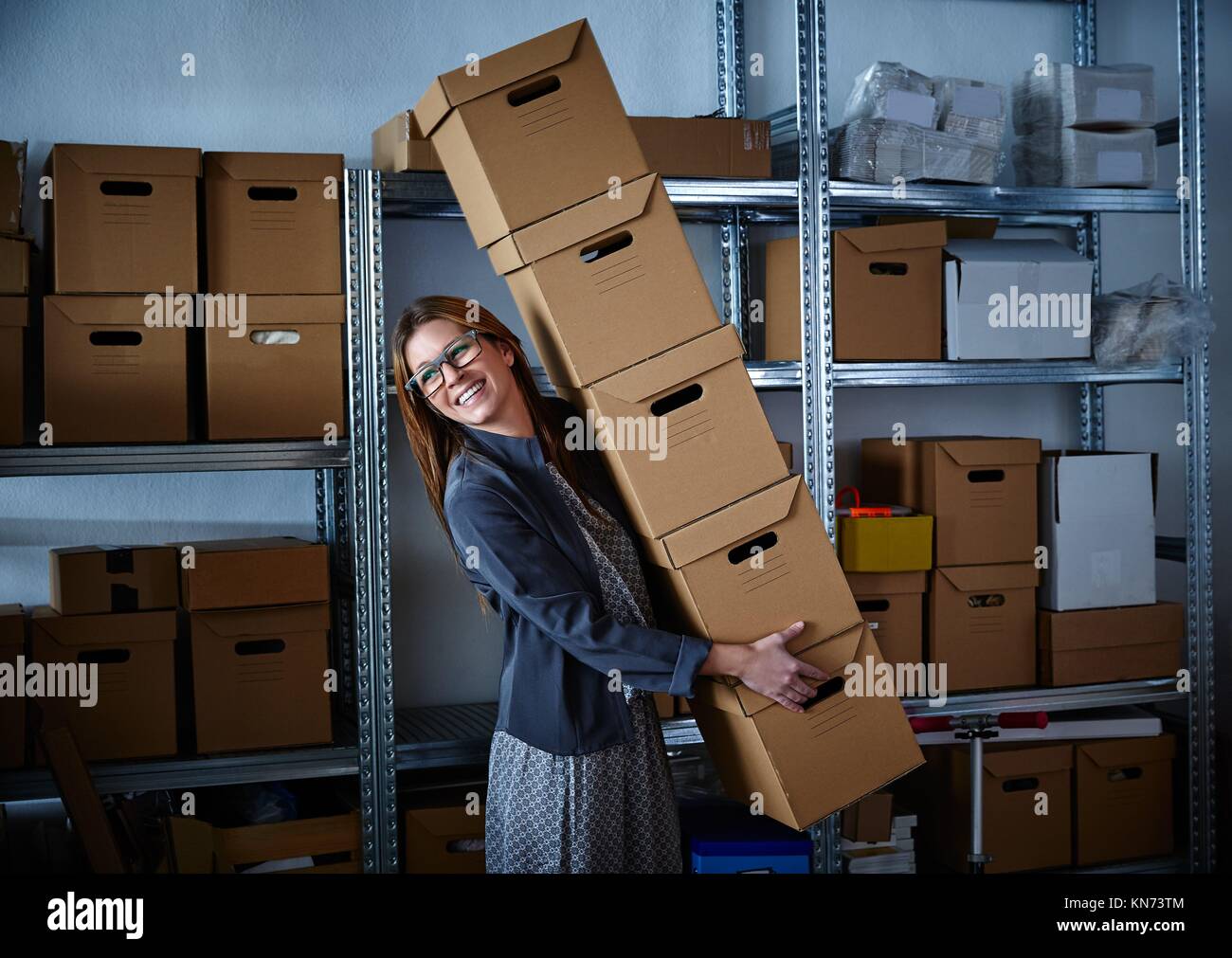 funny businesswoman holding many storage boxes in office warehouse rack ...