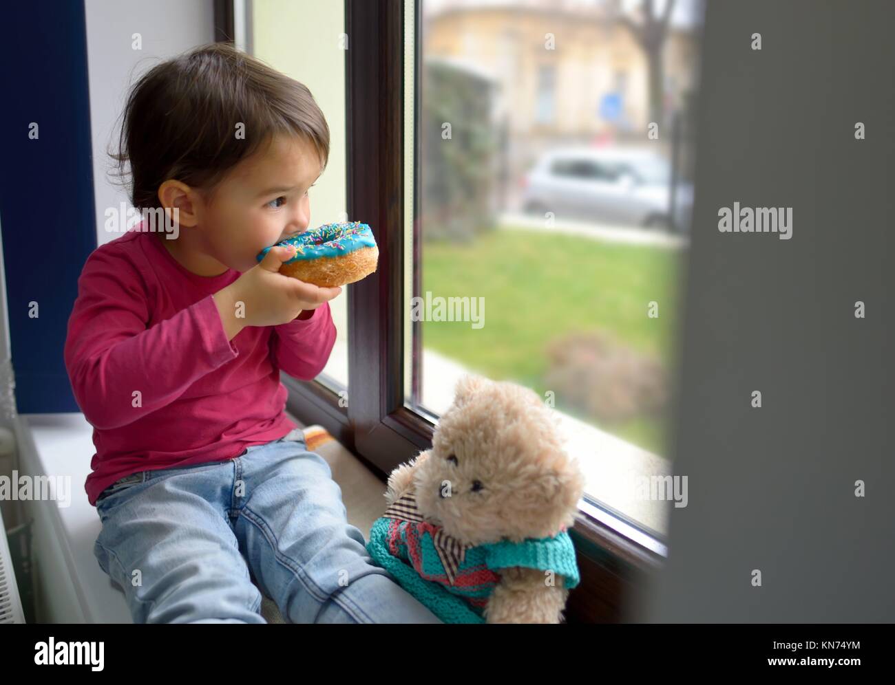 little girl and her bear toy eating donuts Stock Photo - Alamy