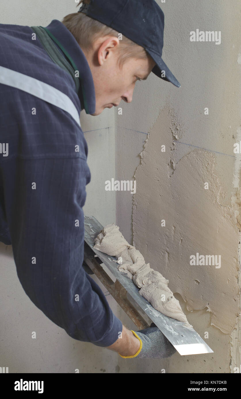 Man gets manually gypsum plaster on the wall Stock Photo - Alamy