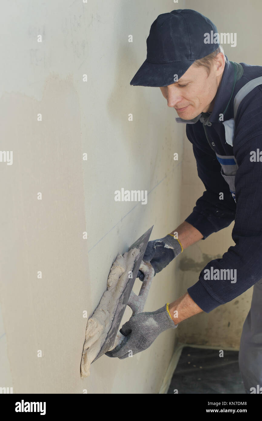 Man gets manually gypsum plaster on the wall Stock Photo - Alamy