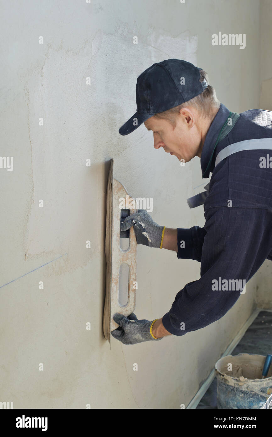 Man gets manually gypsum plaster on the wall Stock Photo - Alamy