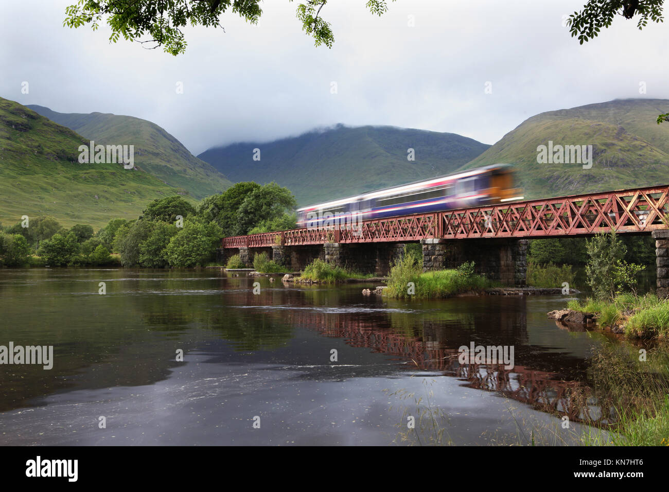 Train, blurred with slow shutter speed, crossing the railway bridge ...