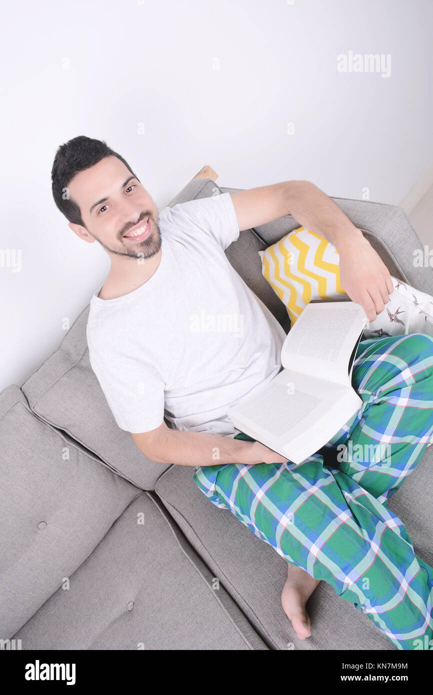 Attractive young man relaxed and reading a book. Indoors Stock Photo ...