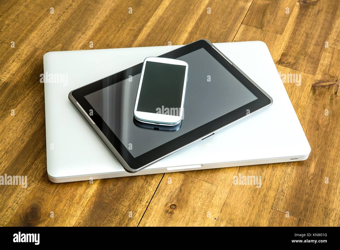 A Laptop computer, a Tablet PC and a Smartphone on a wooden Desktop ...
