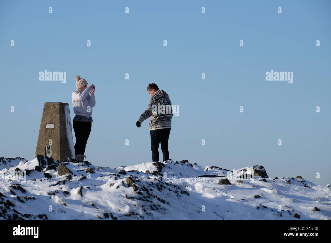 two people stand next to a trig point on top of beacon hill ...