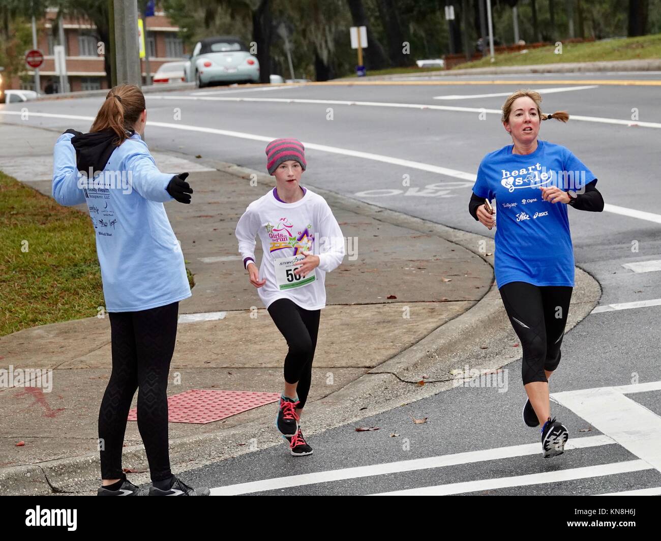 Girl and woman run across intersection while young woman stops traffic ...
