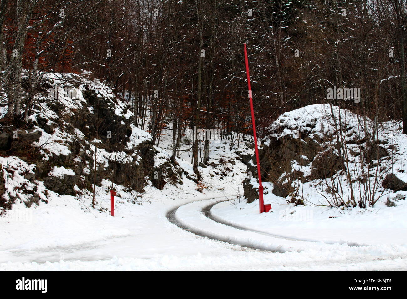Open gate entrance on snow covered forest road blocked by red metal ...