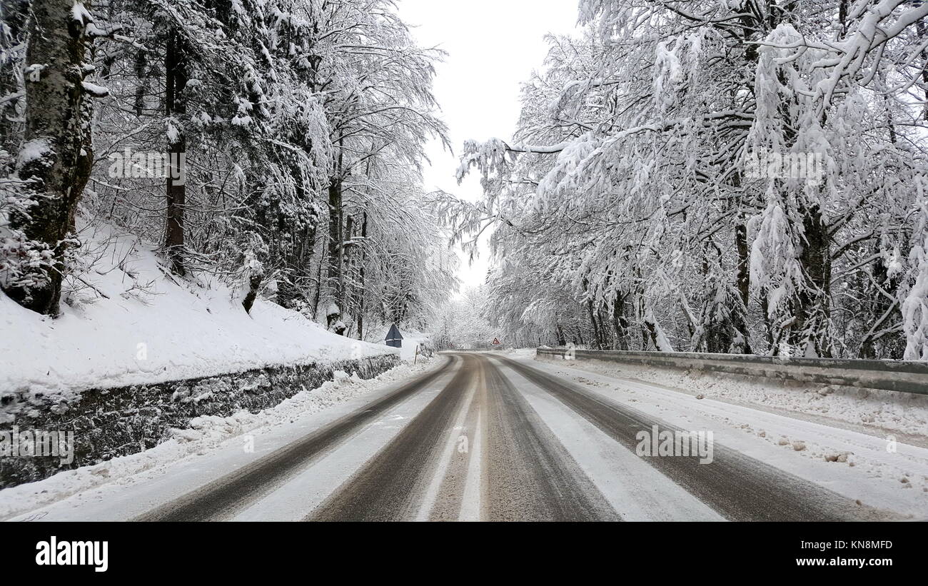 Winter road with traffic tracks visible on snow covered asphalt and ...