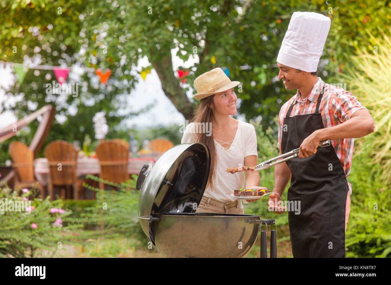 Happy couple cooking meat on barbecue grill, France Stock Photo - Alamy