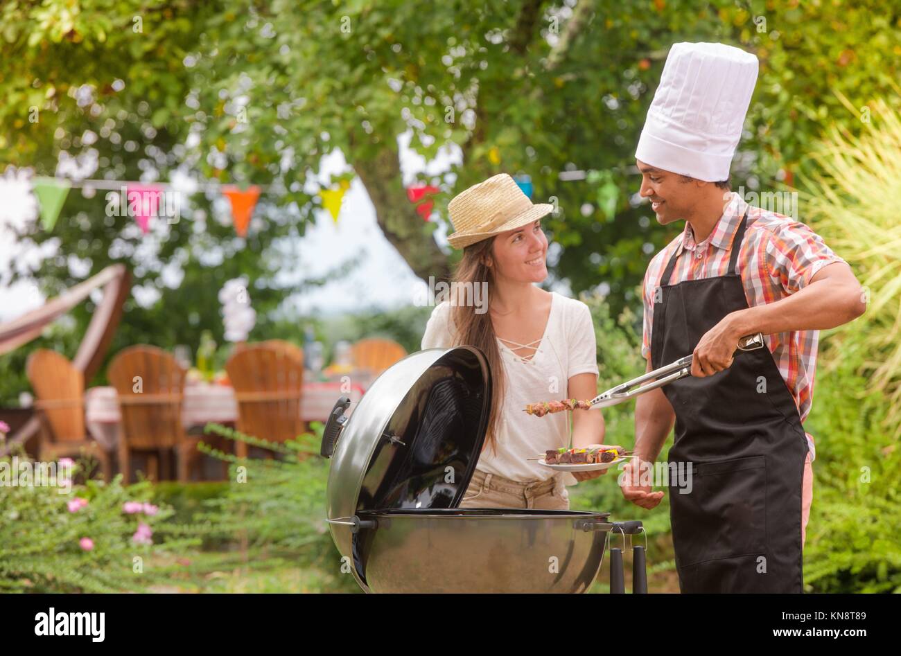 Happy couple cooking meat on barbecue grill, France Stock Photo - Alamy