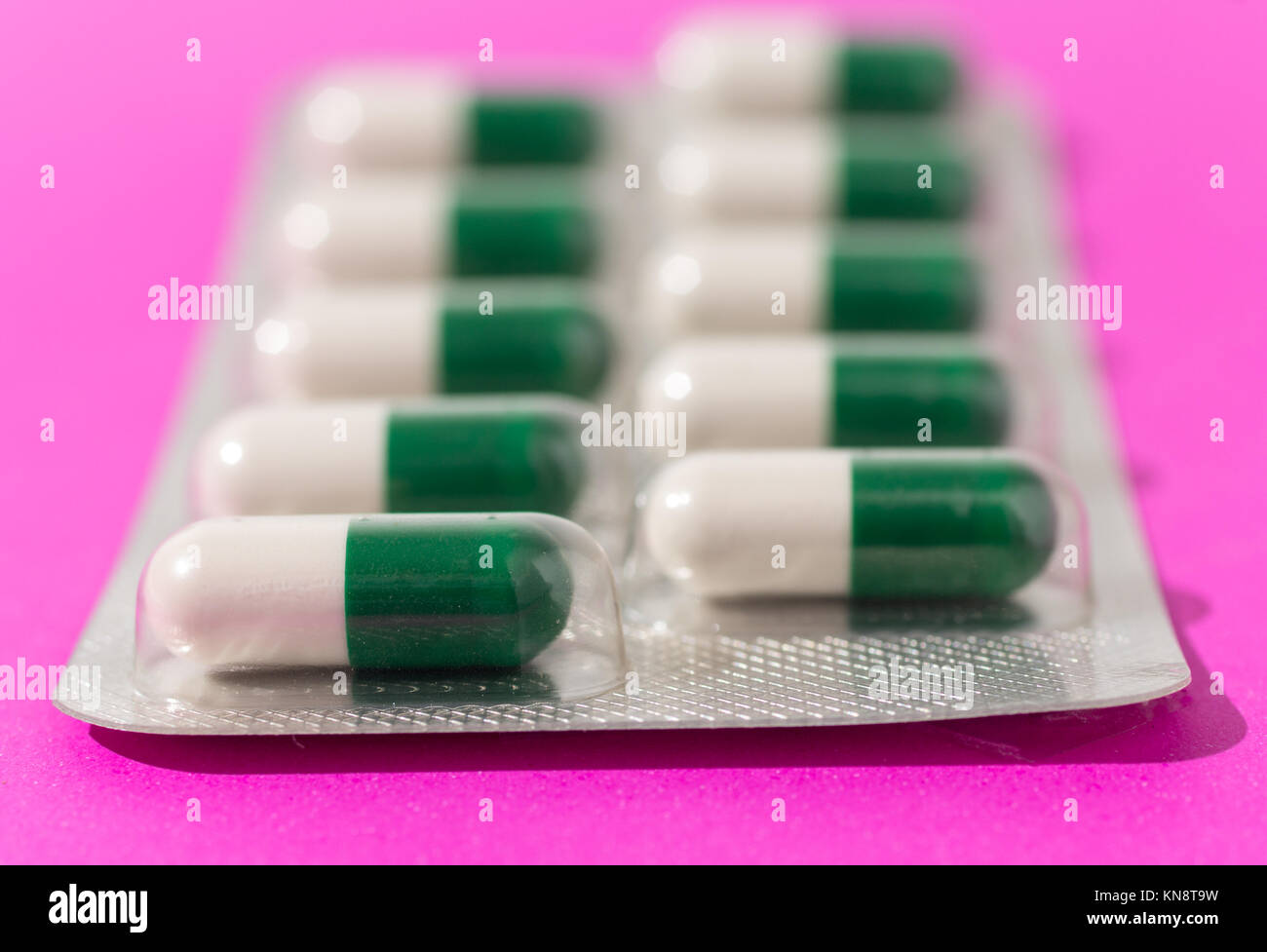 Front view of white and green capsules on medicine box over purple ...