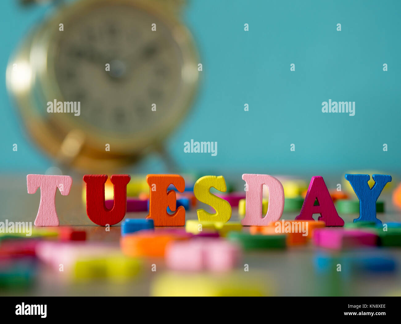 Colorful wooden word TUESDAY on wooden table and vintage alarm clock ...