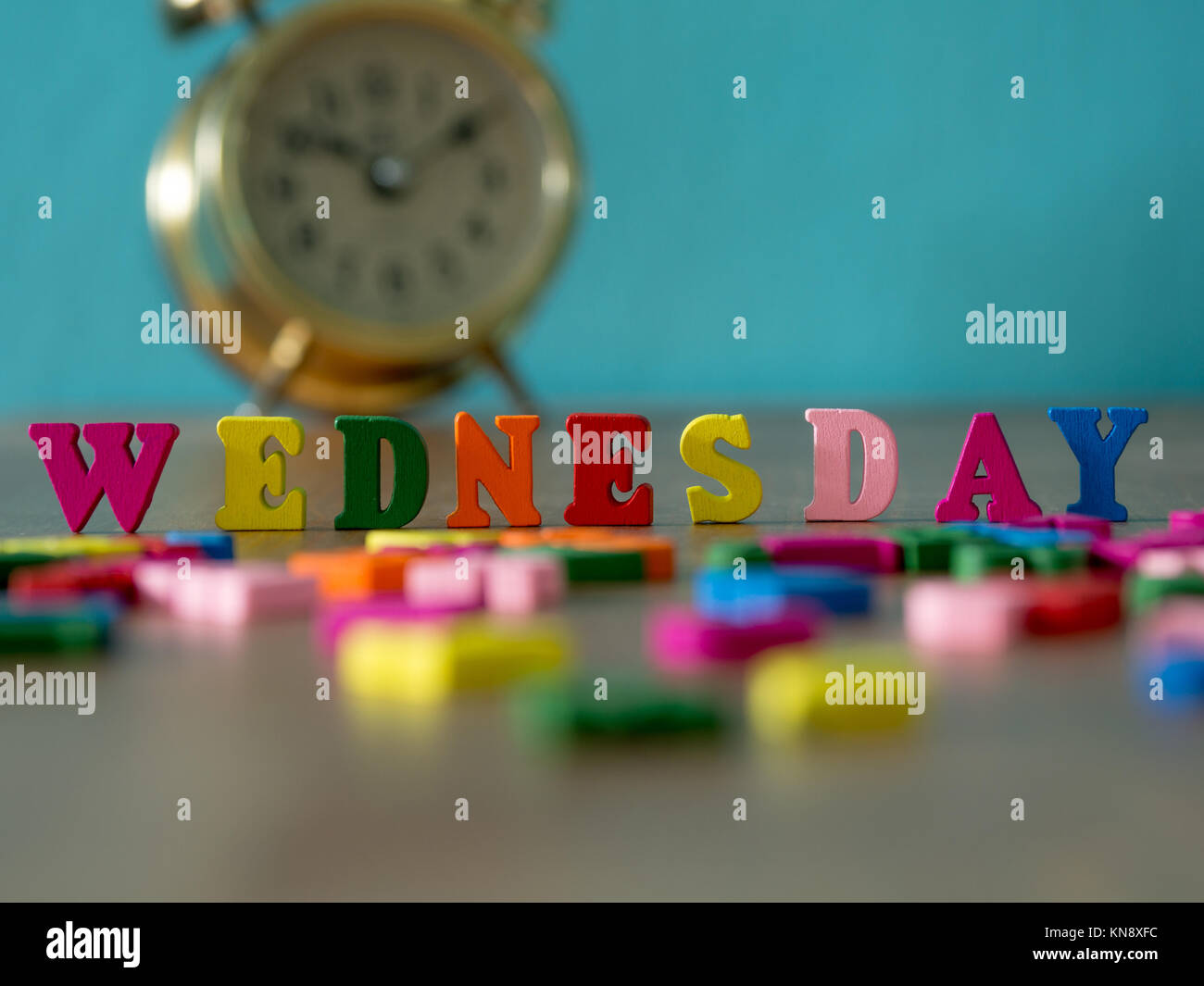 Colorful wooden word WEDNESDAY on wooden table and vintage alarm clock ...