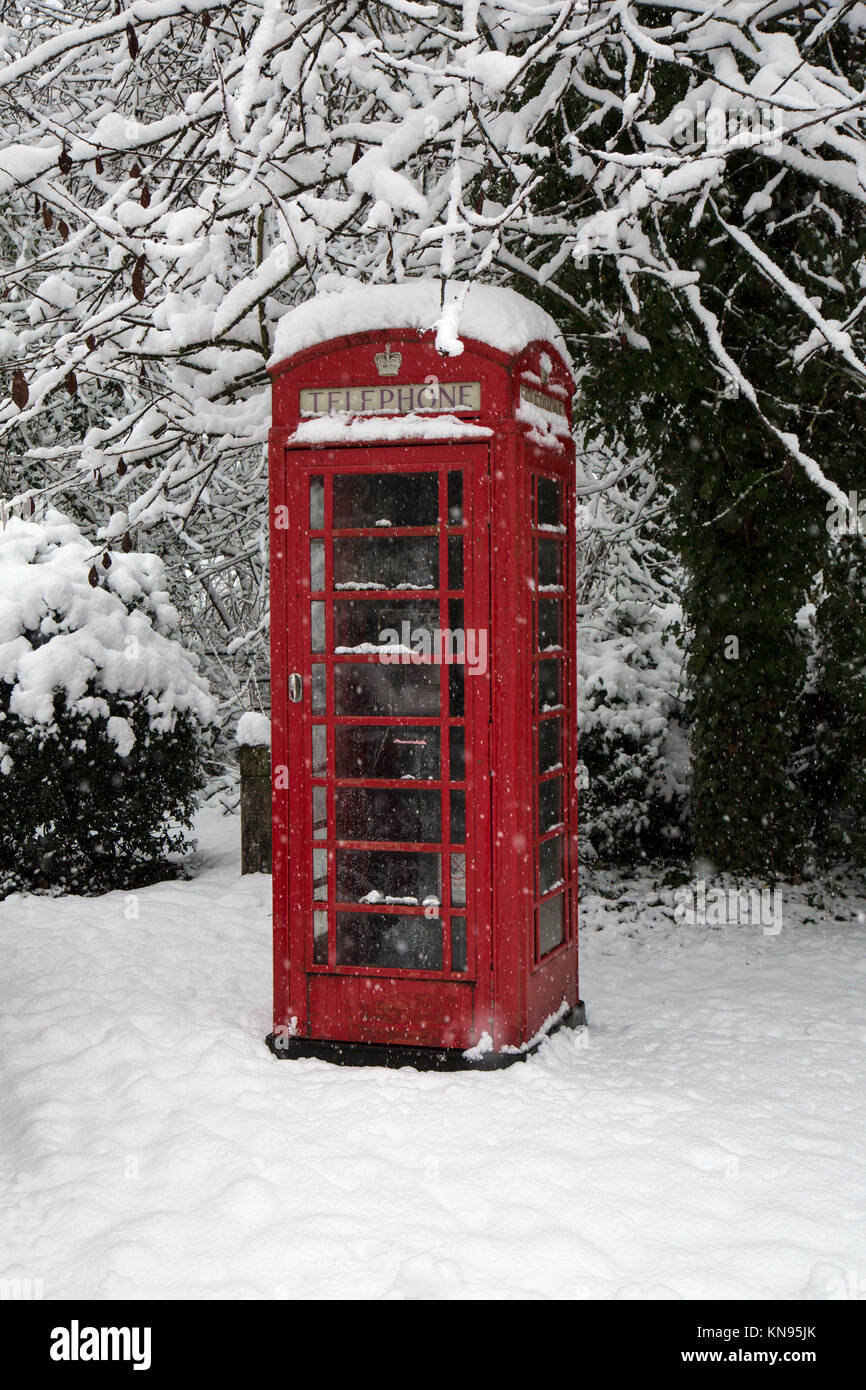 A red British telephone box covered in snow in winter, with snow ...