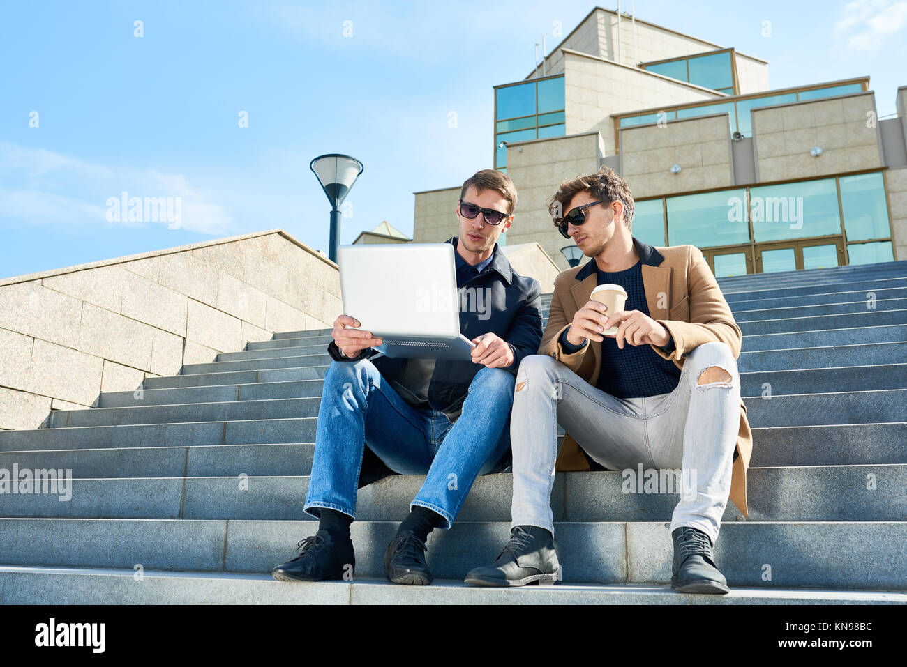 Two Young Men Using Laptop in City Stock Photo - Alamy