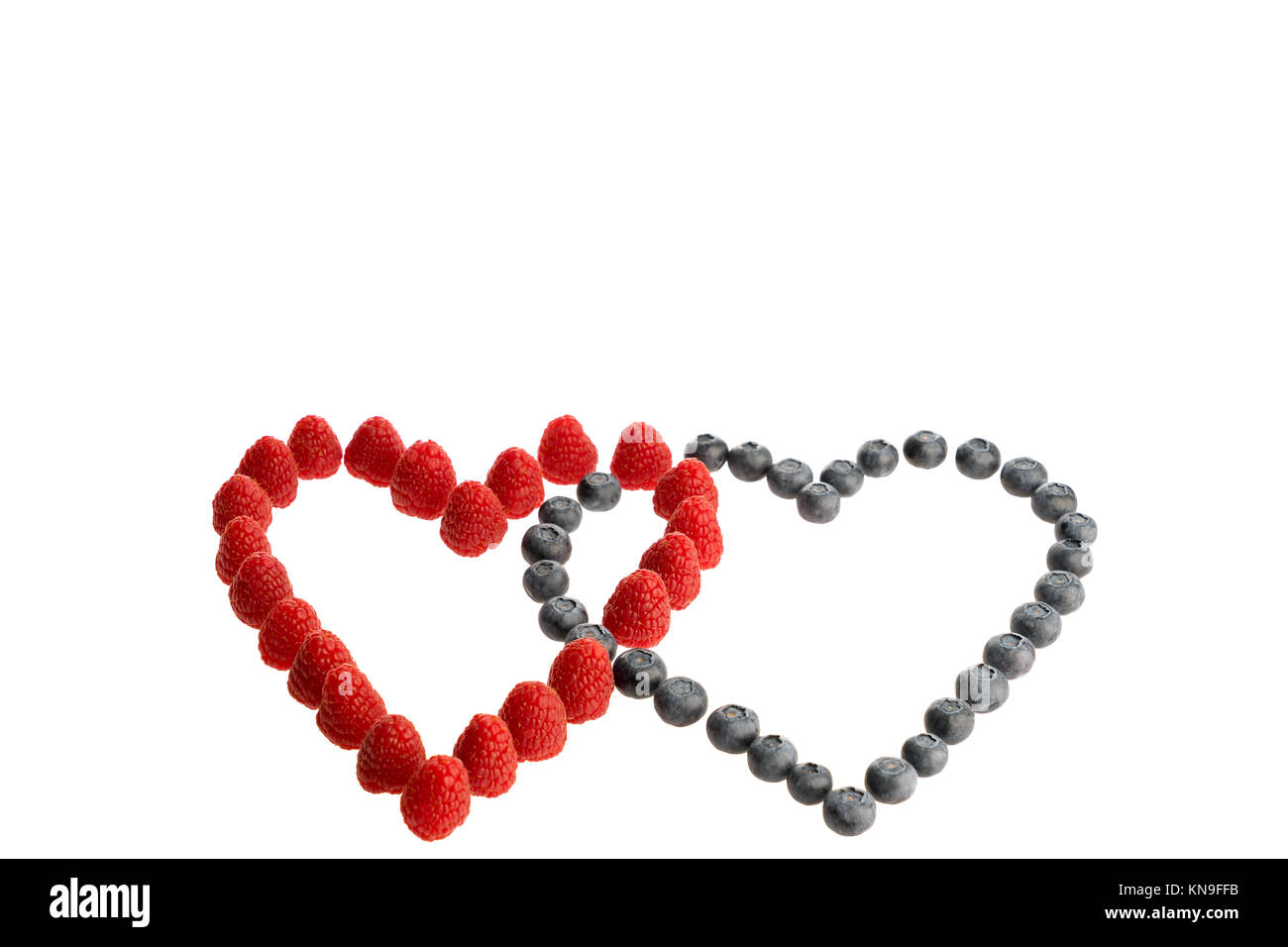 Fresh raspberries and blueberries lying in two heart shapes isolated in ...