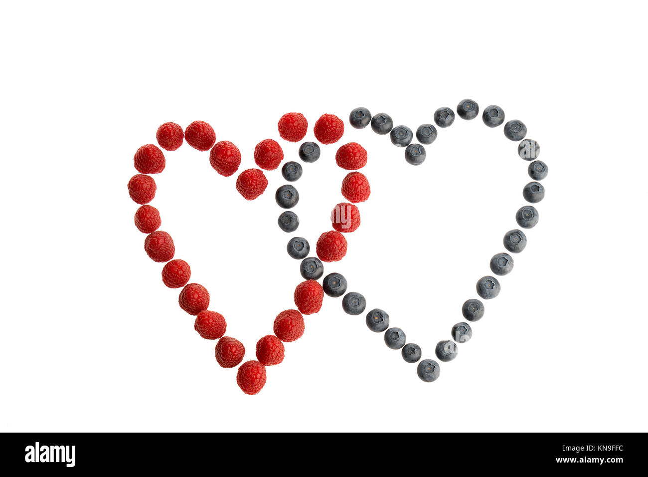 Fresh raspberries and blueberries lying in two heart shapes isolated in ...