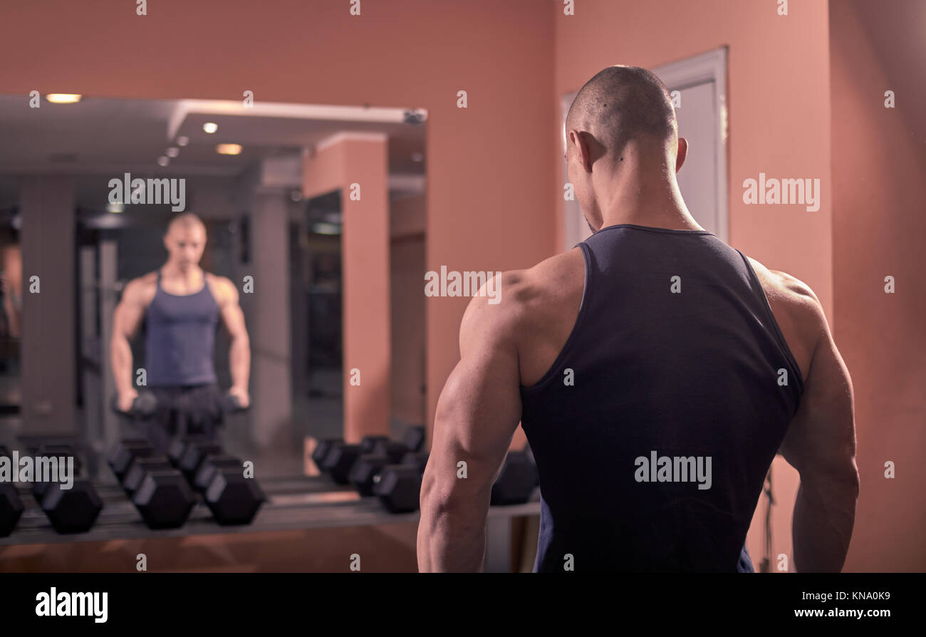 one young bodybuilder back looking in mirror, looking at self, rear ...