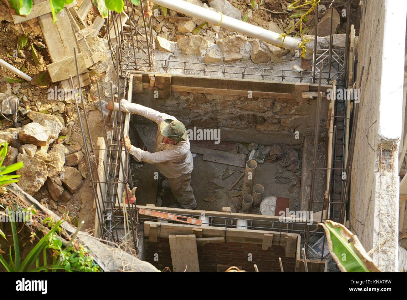Mexican man building the base for a swimming pool in rocky hillside of ...
