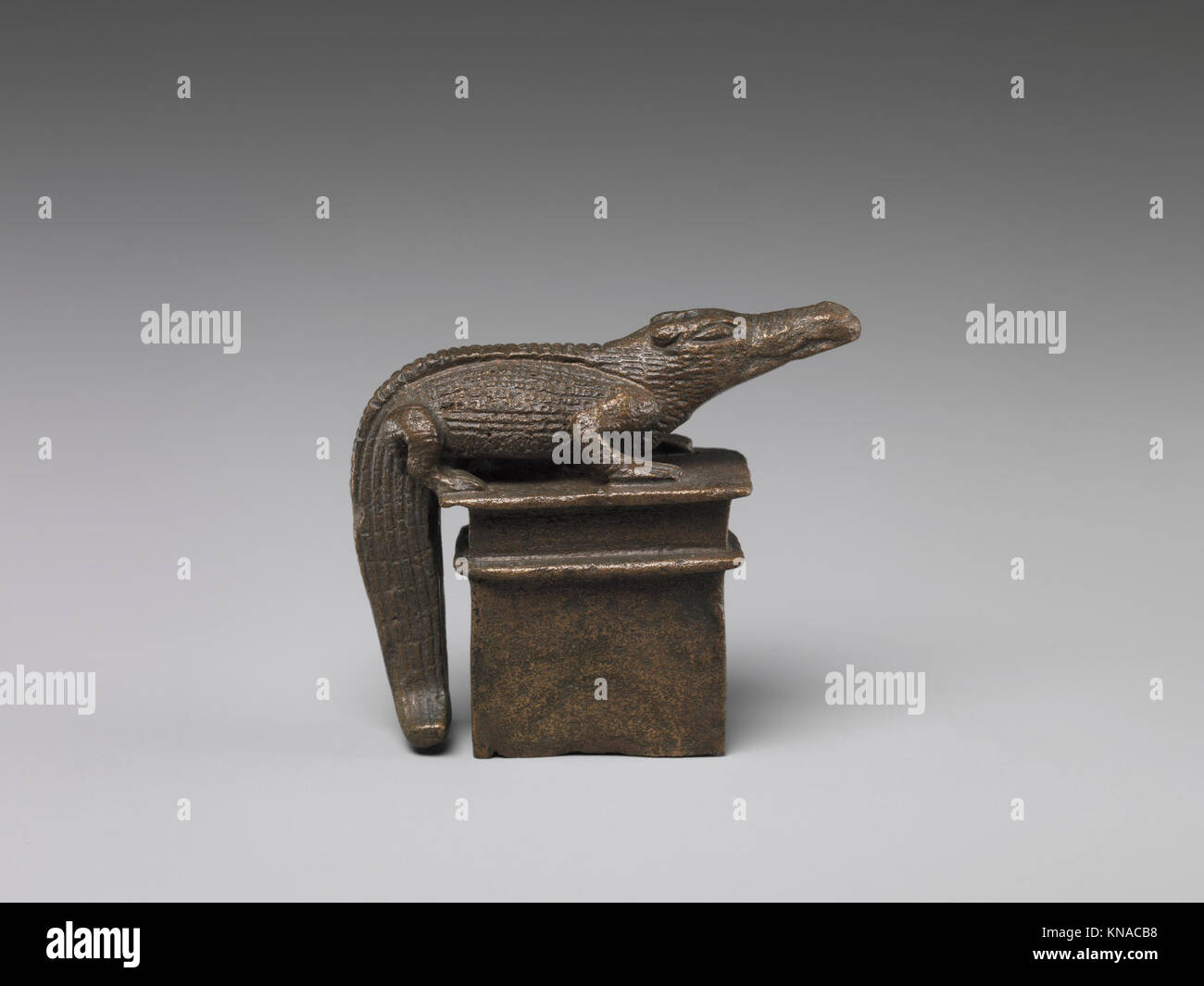 A crocodile sculpture positioned on a shrine-shaped base, combining ...
