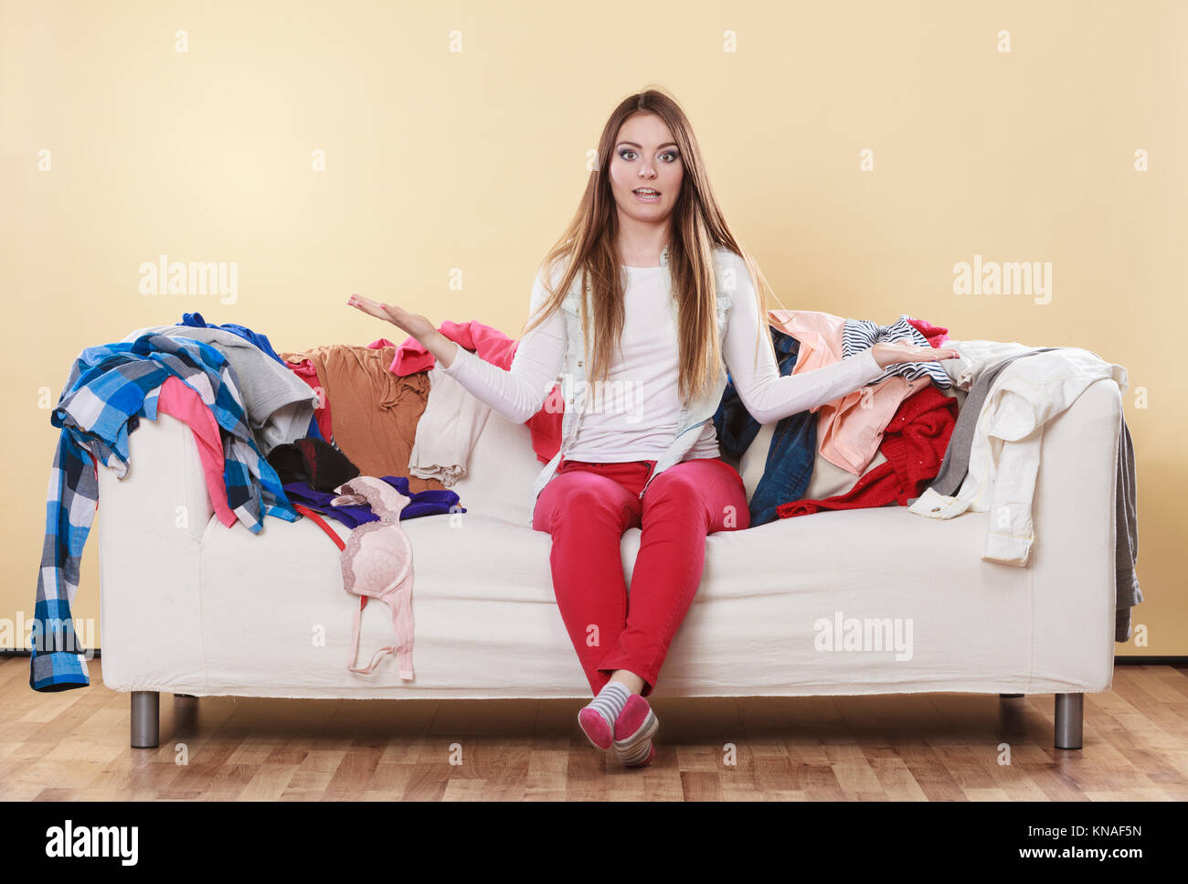 Helpless woman sitting on sofa couch in messy living room shrugging ...