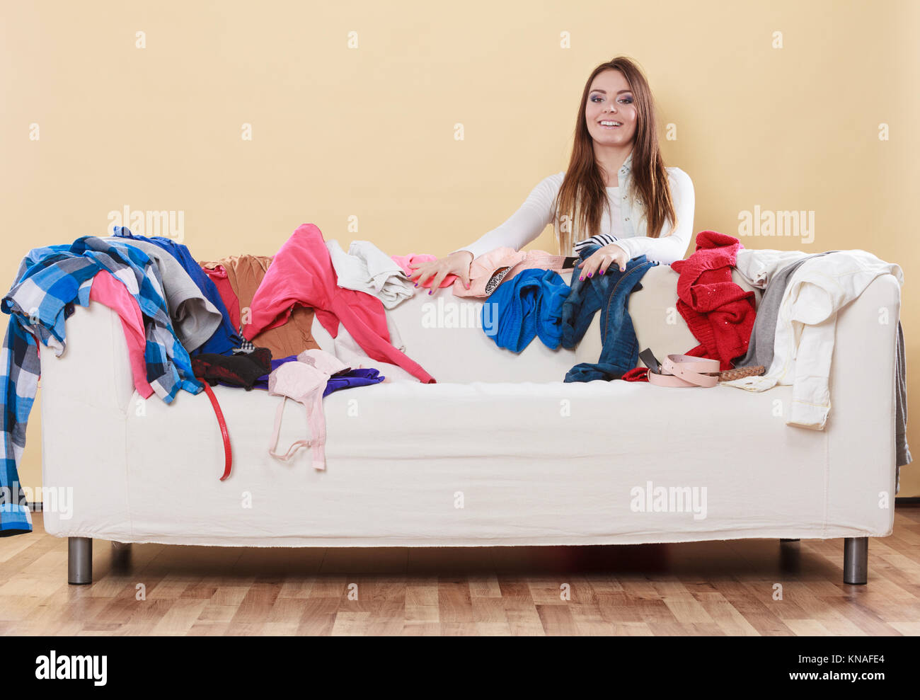 Happy woman behind sofa couch in messy living room. Young girl ...