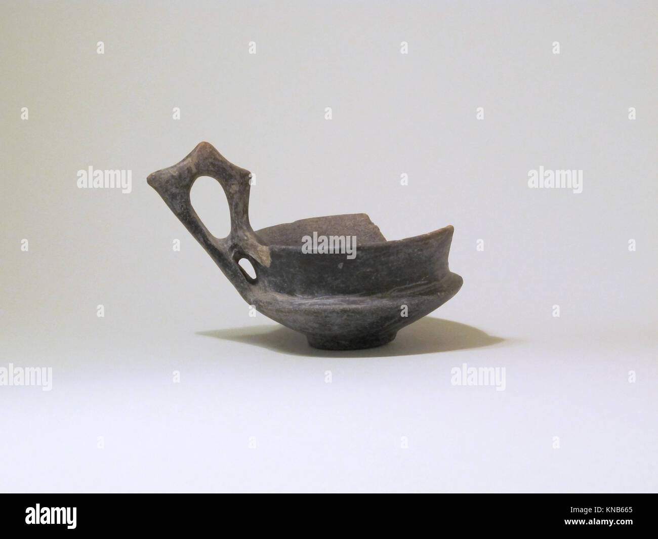 This ancient metal cup exhibits detailed craftsmanship and functional ...