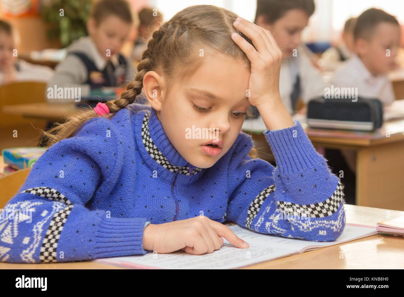 First-grader at a lesson reads the text line by line leading a finger ...