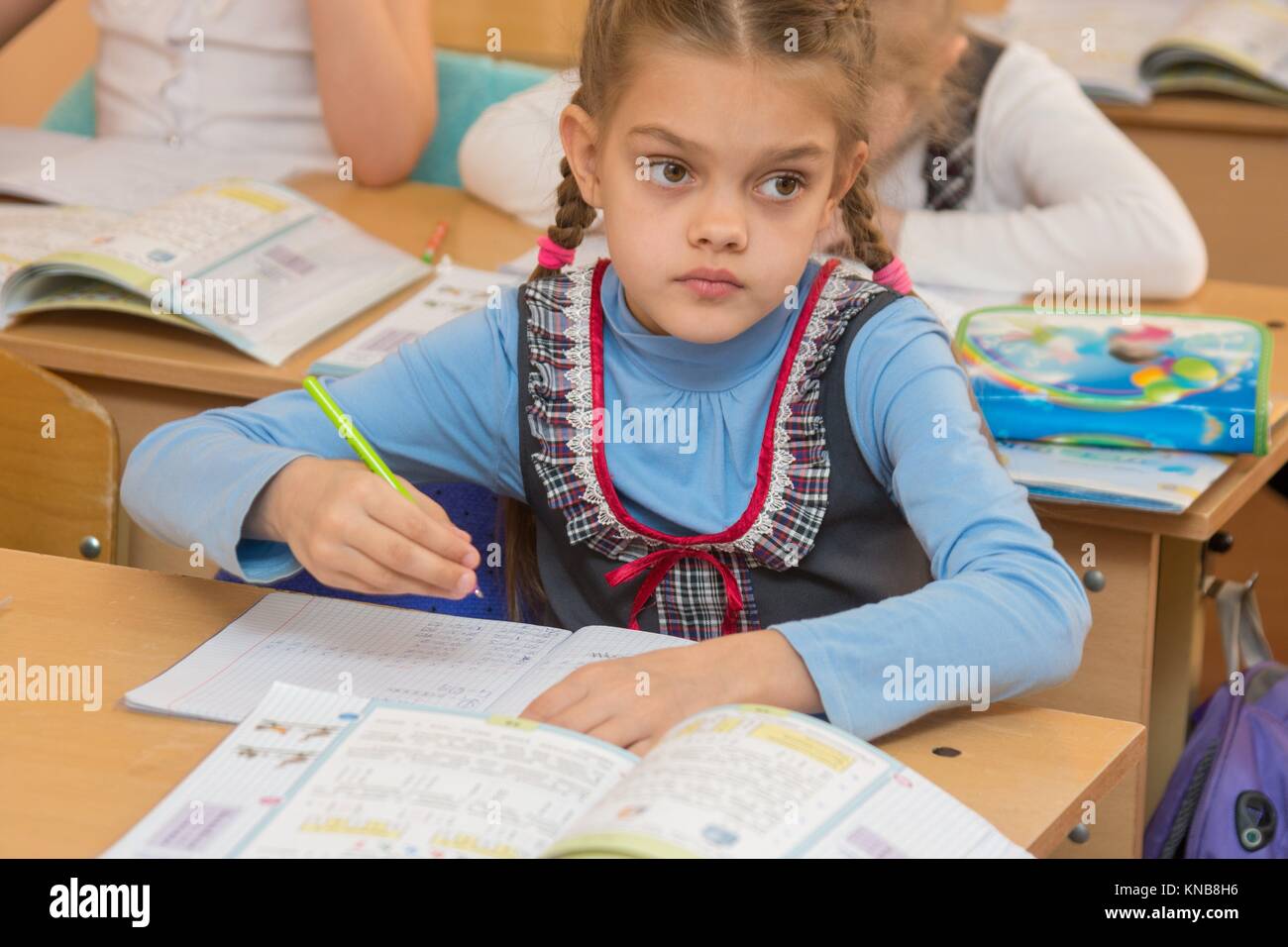 First-grader at a lesson of mathematics solves examples and look at the ...