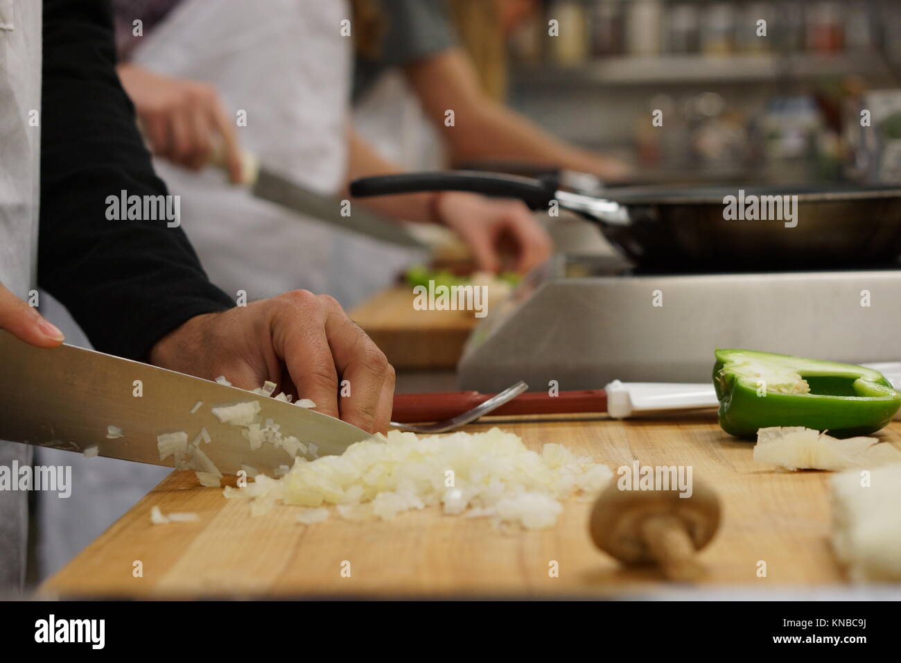 Close up images of hands in a cooking class, cutting vegetables on a ...