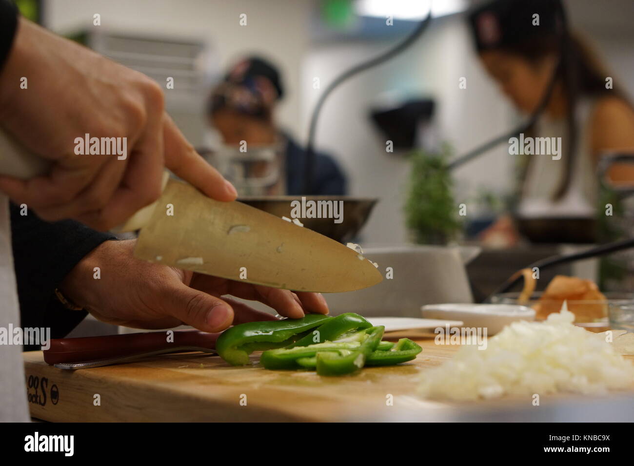 Close up images of hands in a cooking class, cutting vegetables on a ...