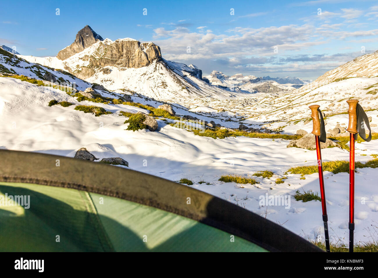 Tent and hiking sticks in snowy mountain landscape. Trekking in Swiss ...