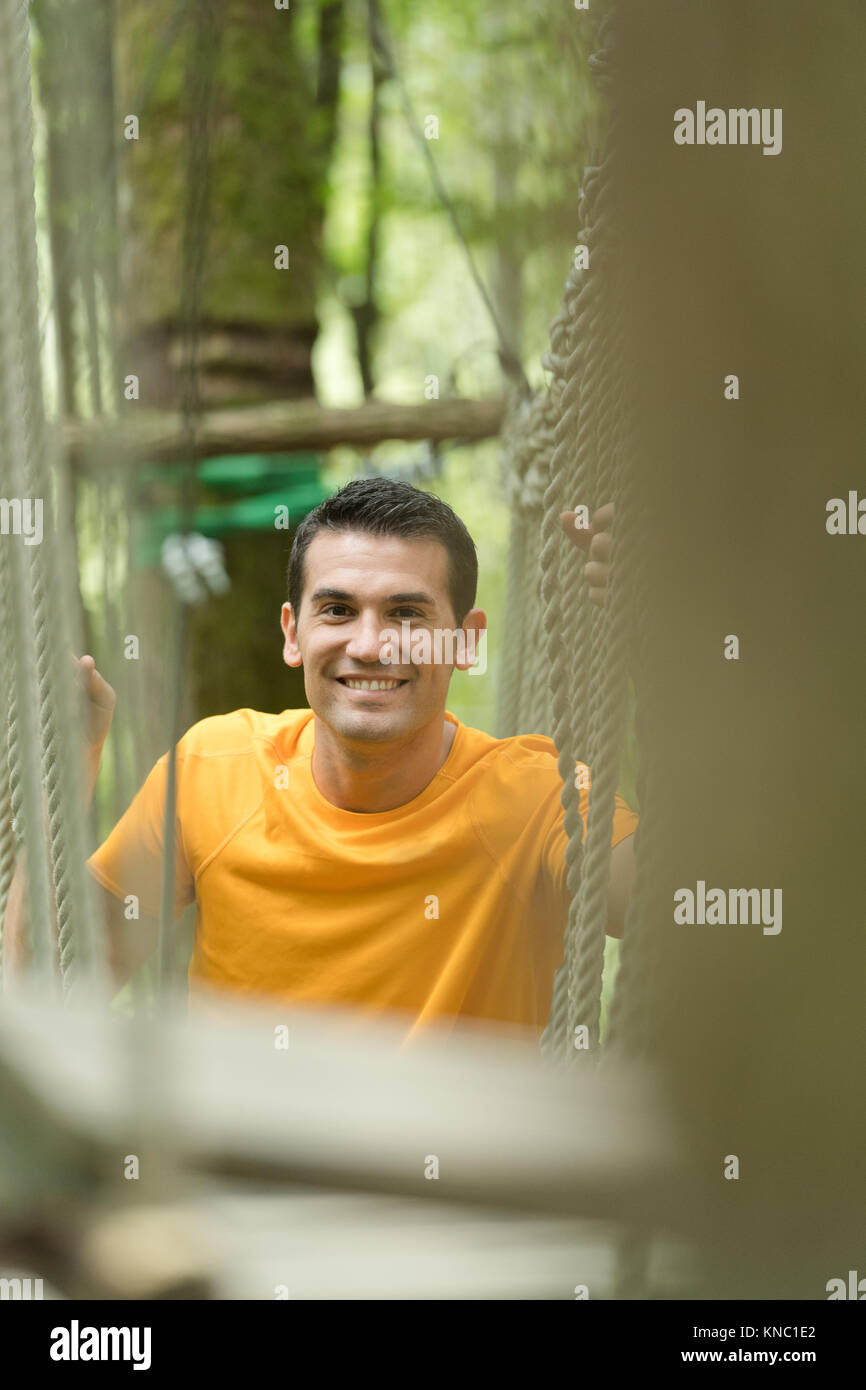 handsome smiling man crossing rope bridge Stock Photo - Alamy