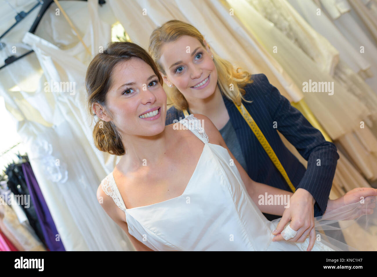 female trying on wedding-dress with women assistant Stock Photo - Alamy