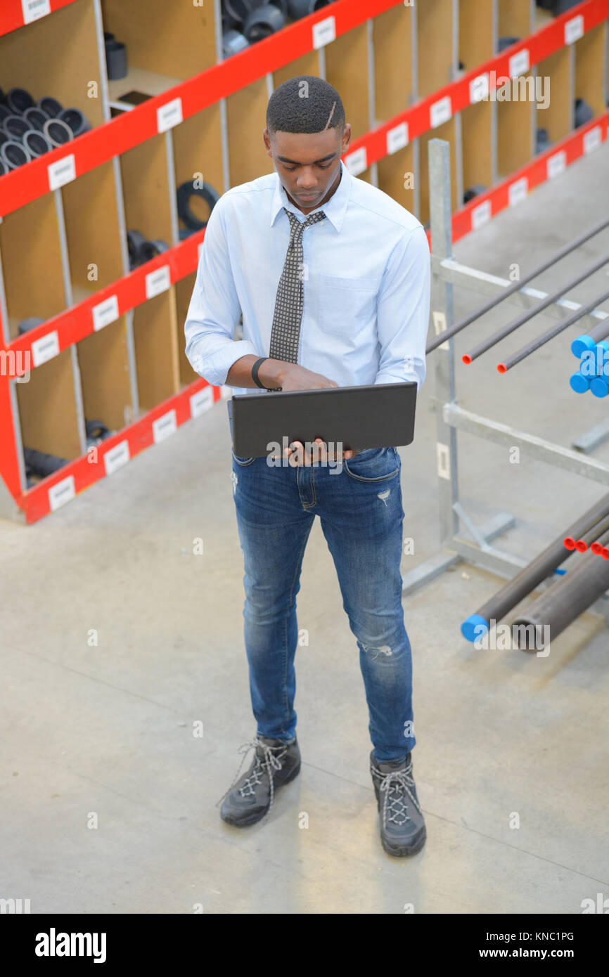 black manager with laptop in warehouse Stock Photo - Alamy