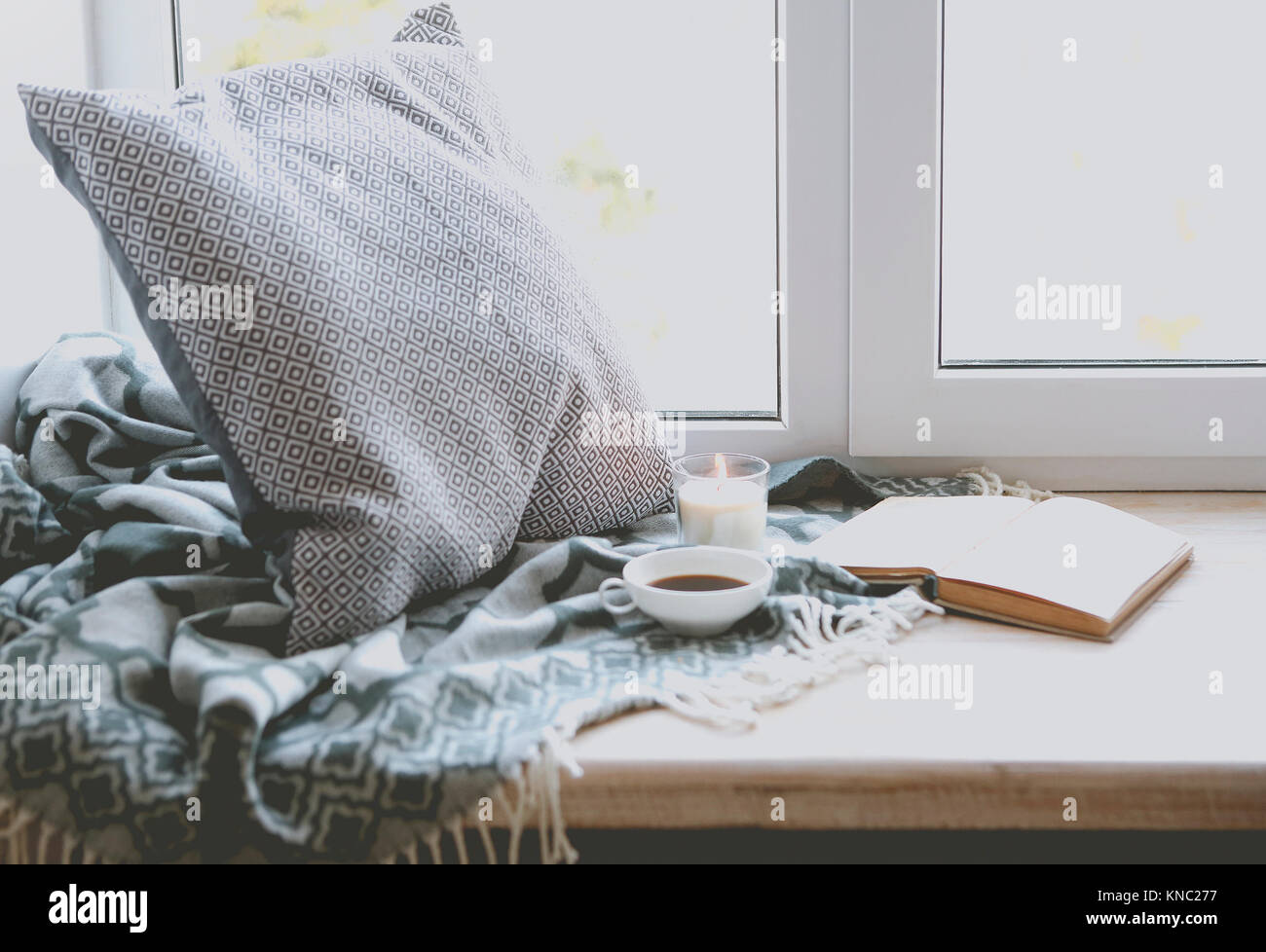 Cup of coffee, candle and book near window Stock Photo - Alamy