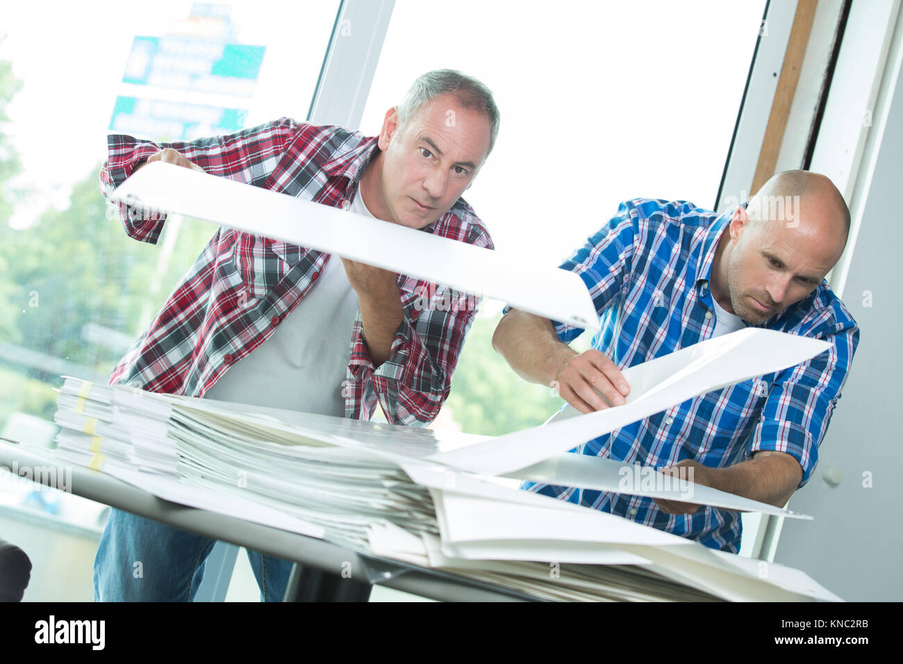 Two workers looking through stack of papers Stock Photo - Alamy
