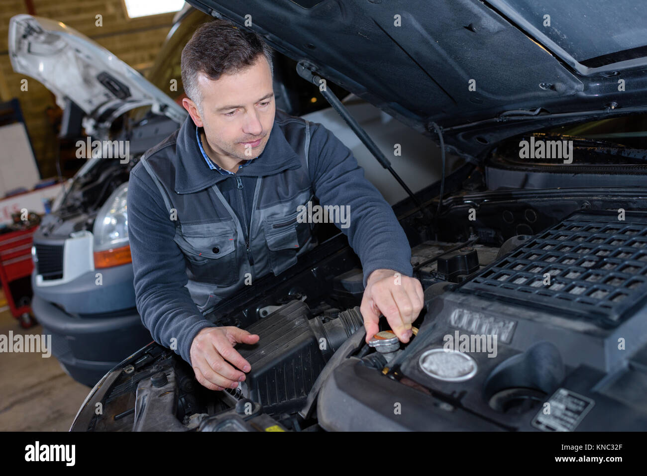 mechanic unscrewing the oil tank in auto repair Stock Photo - Alamy