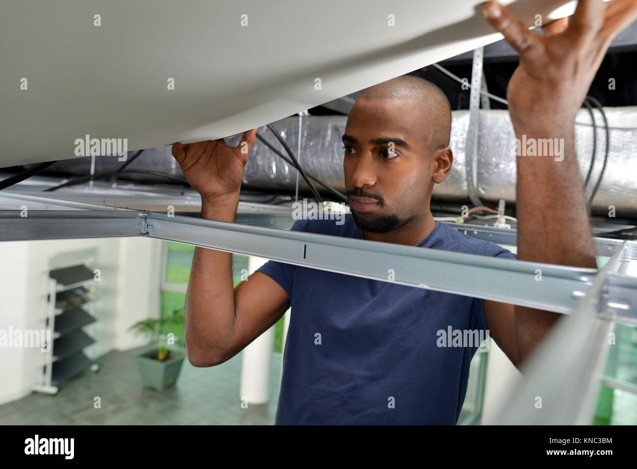 Builder replacing ceiling panel Stock Photo - Alamy