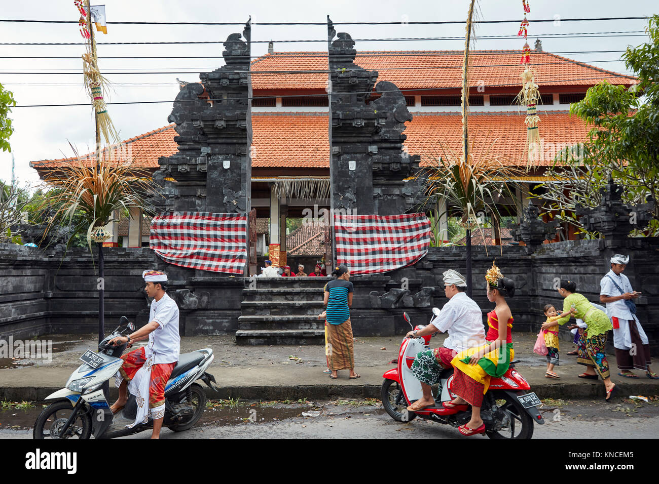 People wearing traditional Balinese clothing go to a local temple near ...