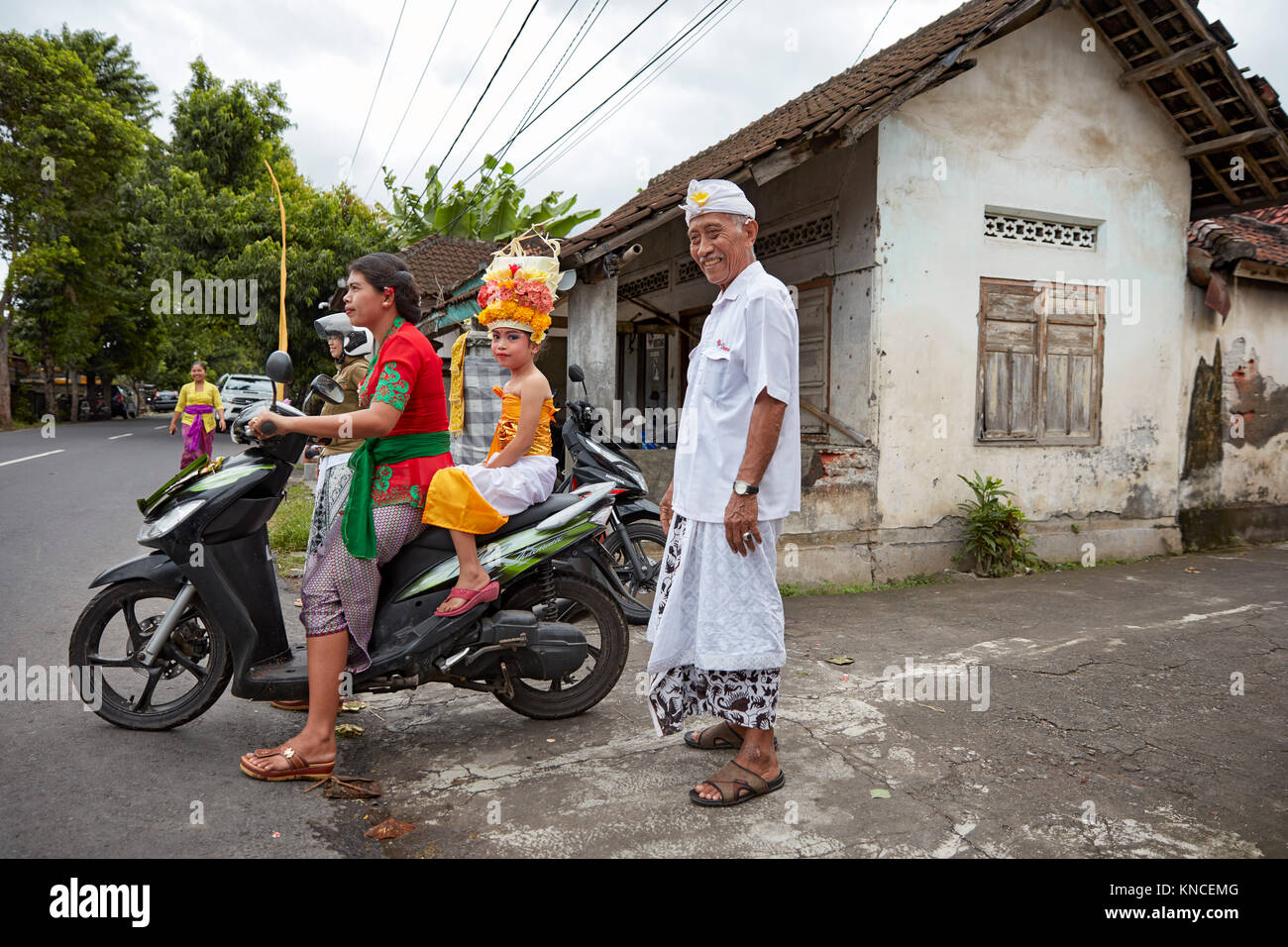 People wearing traditional Balinese clothing go to a local temple near ...